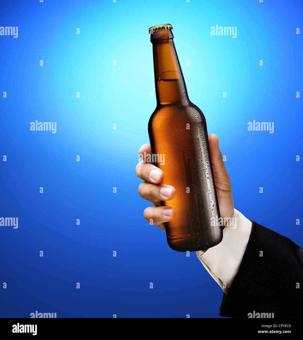 Bottle of beer in a man's hand on a blue background Stock Photo - Alamy