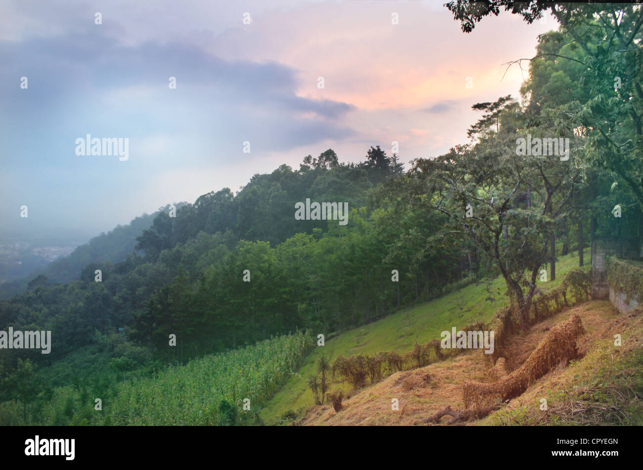 Cloudy colorful sunset sky in the lush green, farm and forested hills ...