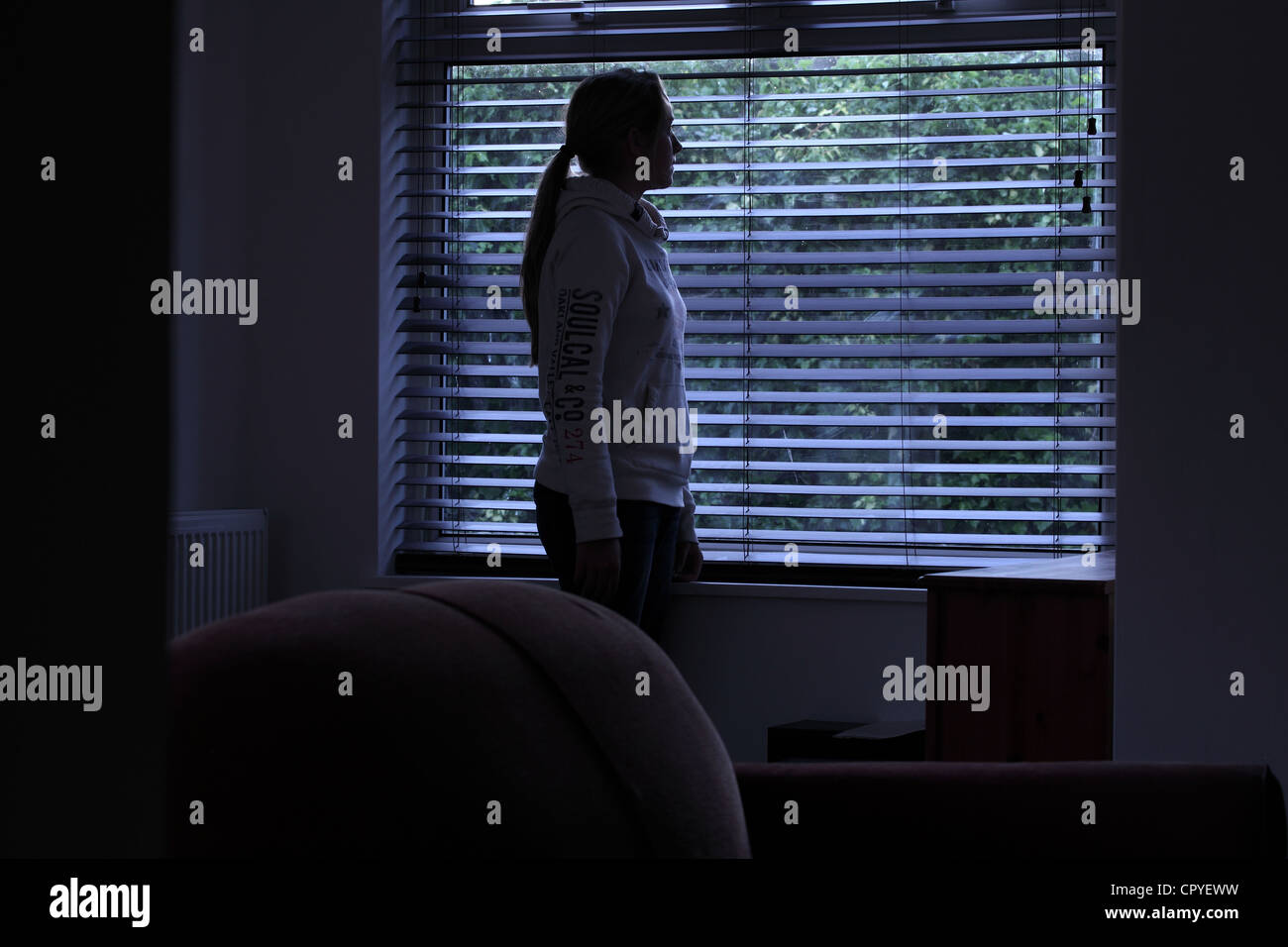 Woman in dark looking through blinds hi-res stock photography and ...