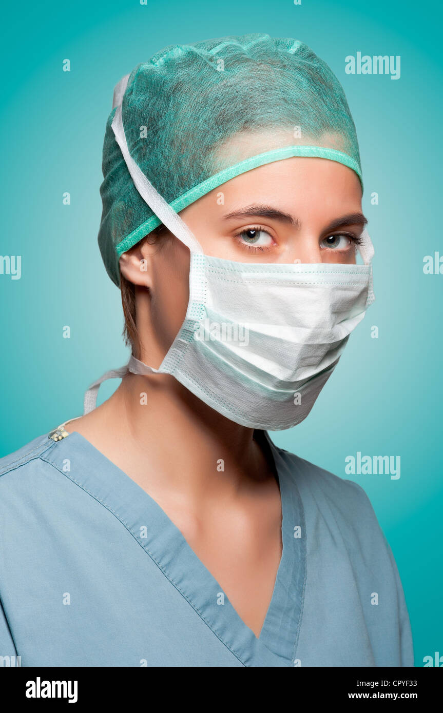 Closeup portrait of a female surgeon, with face mask, in a green ...