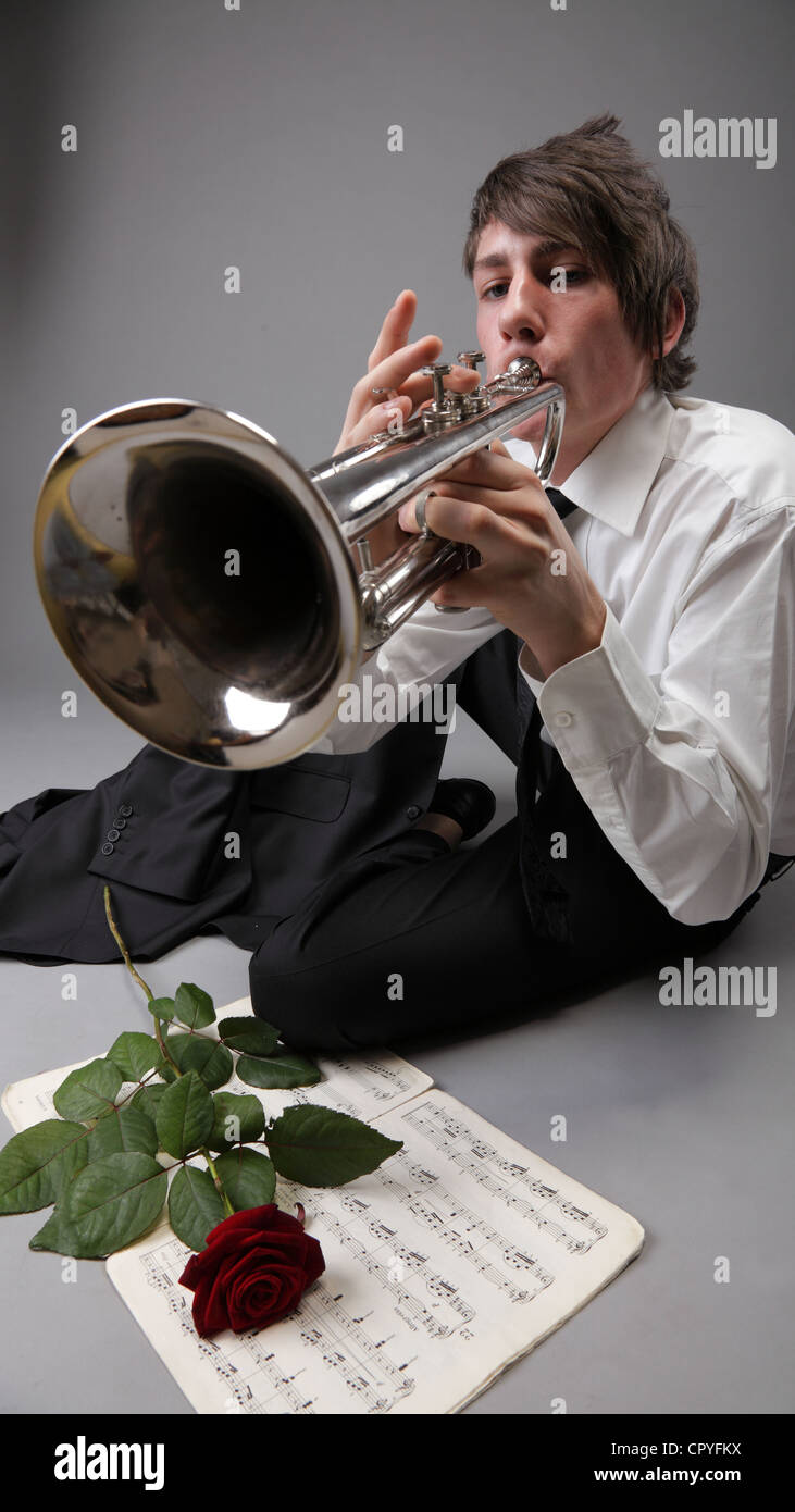 Portrait of a young jazz man playing his Trumpet grey background. Love ...