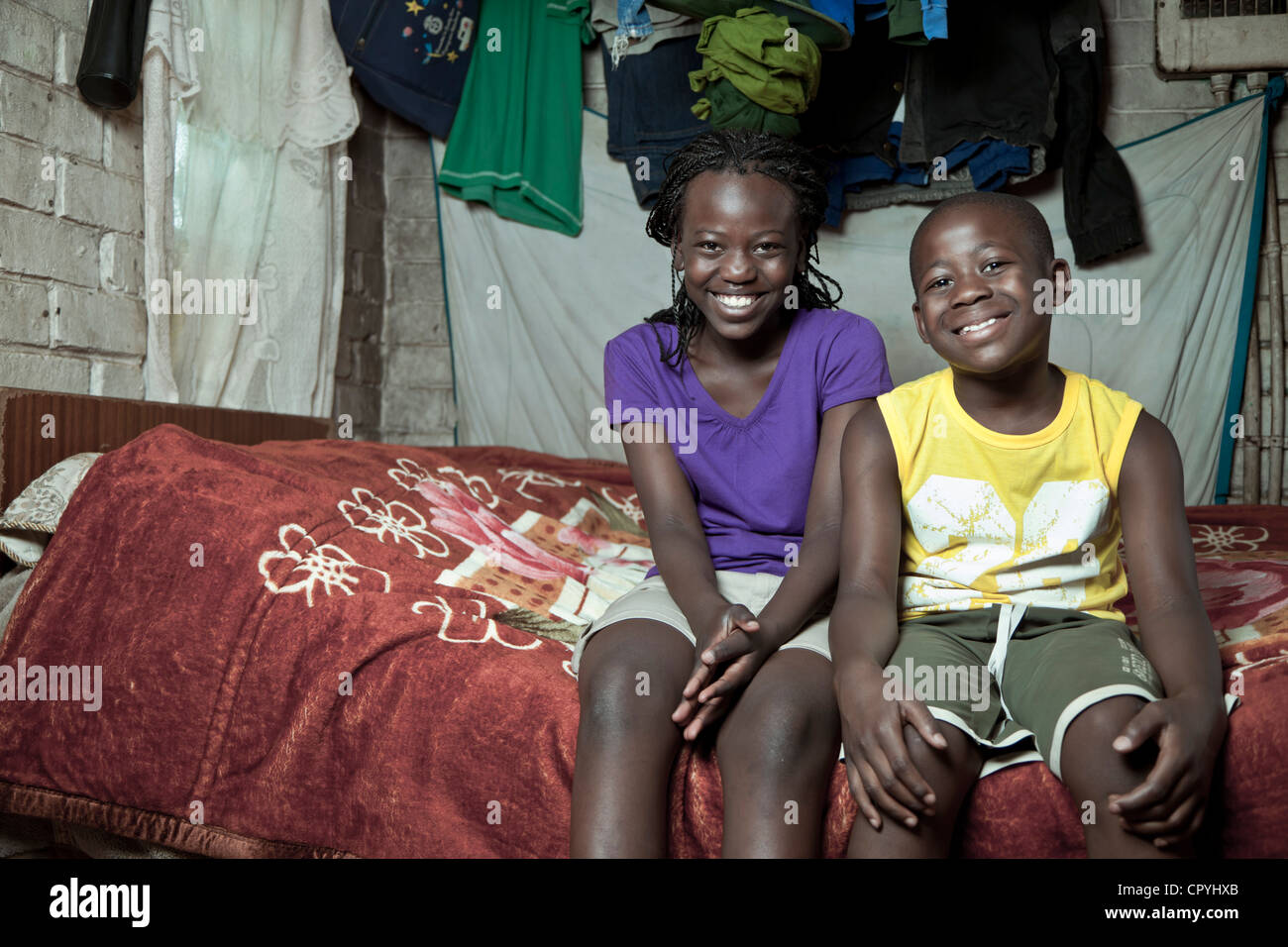 Two young African siblings sit together on a bed indoors Stock Photo ...