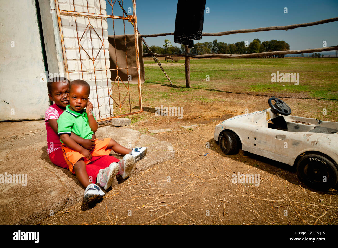Young African siblings sitting in front of their rural home Stock Photo ...