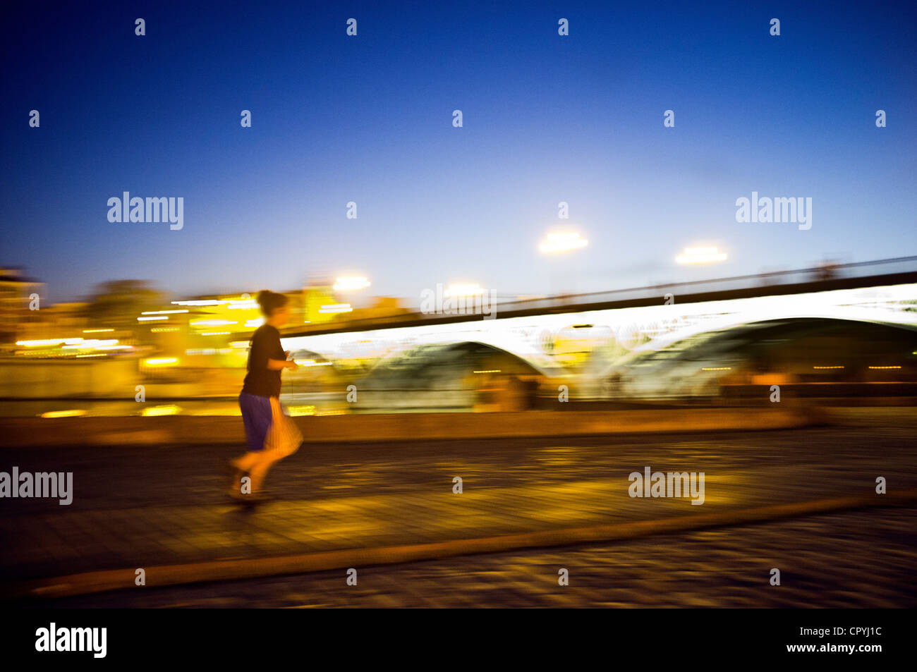 Panning shot of a runner by Triana Bridge at dusk, Seville, Spain Stock ...