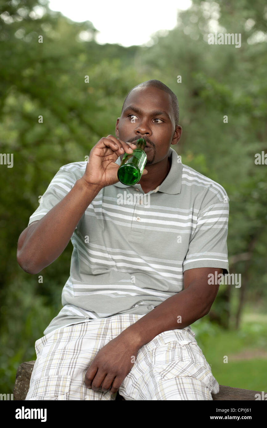 African Man sits outside drinking a beer Stock Photo - Alamy