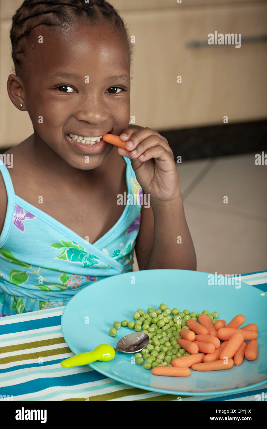 Young African child eating vegetables, looking at camera Stock Photo ...