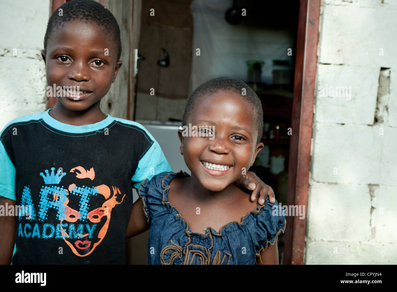 Two African siblings stand outside their rural home, smiling Stock ...