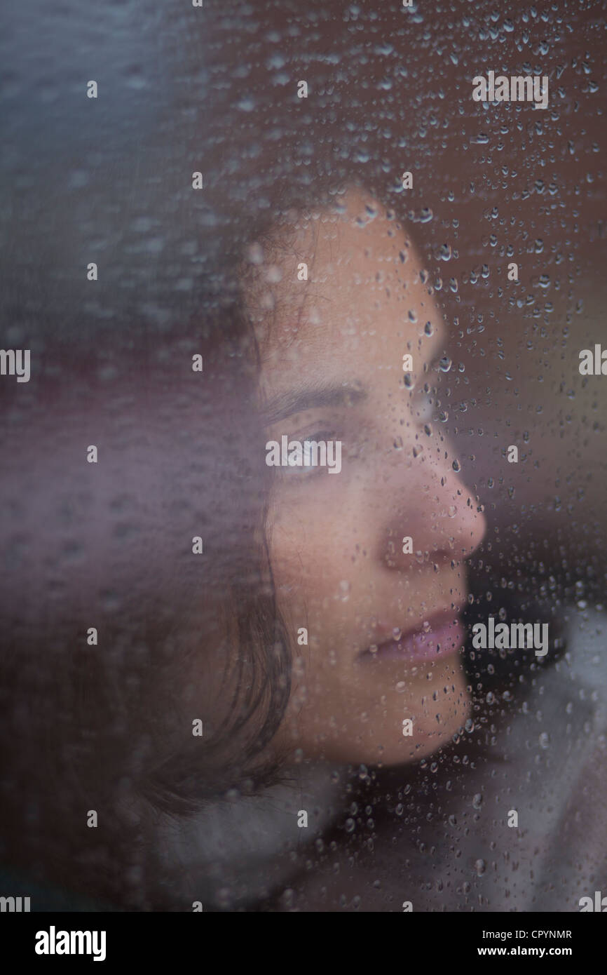 Pensive woman behind a window with rain drops Stock Photo - Alamy