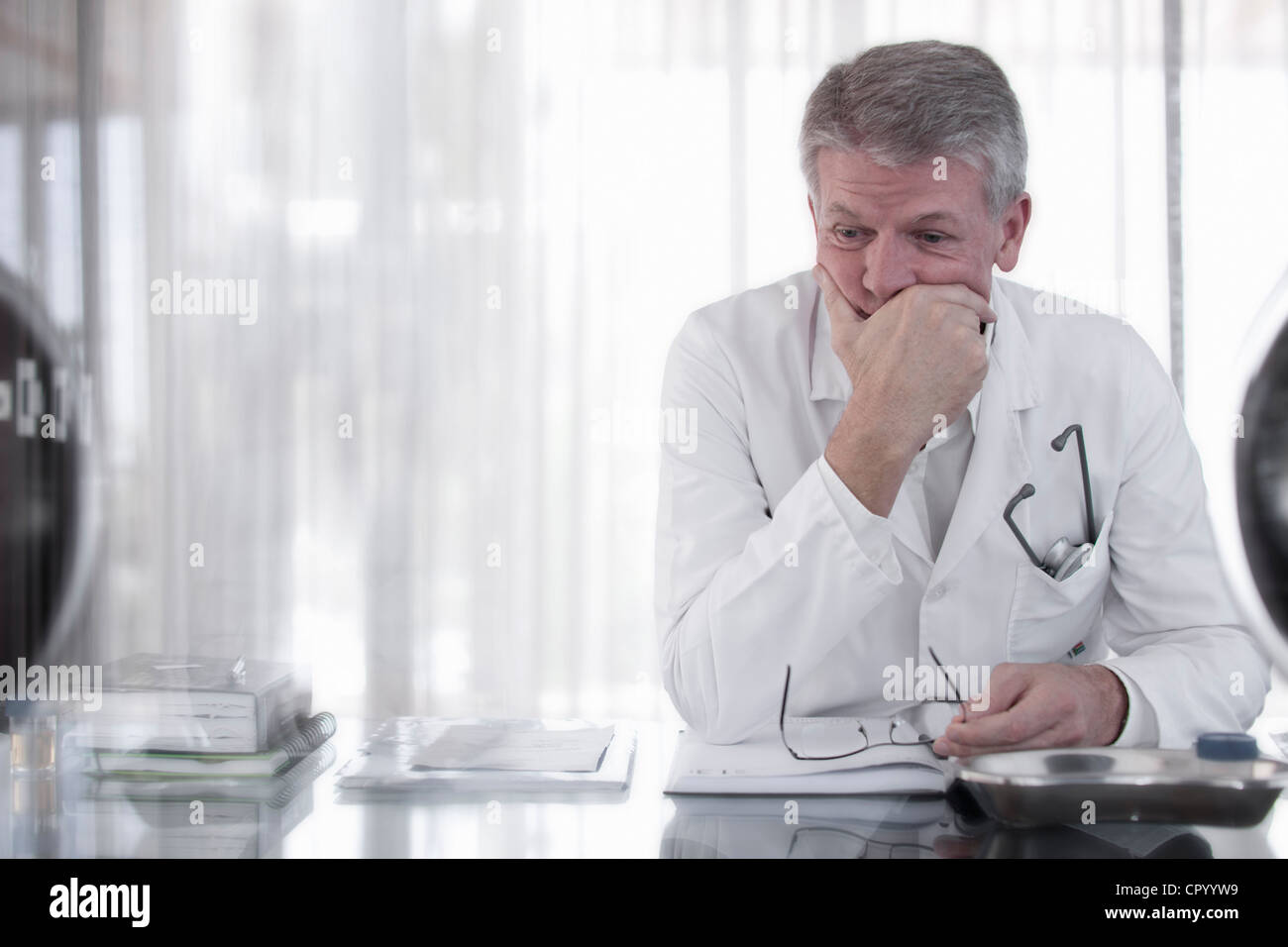 Doctor resting chin in hand in office Stock Photo - Alamy