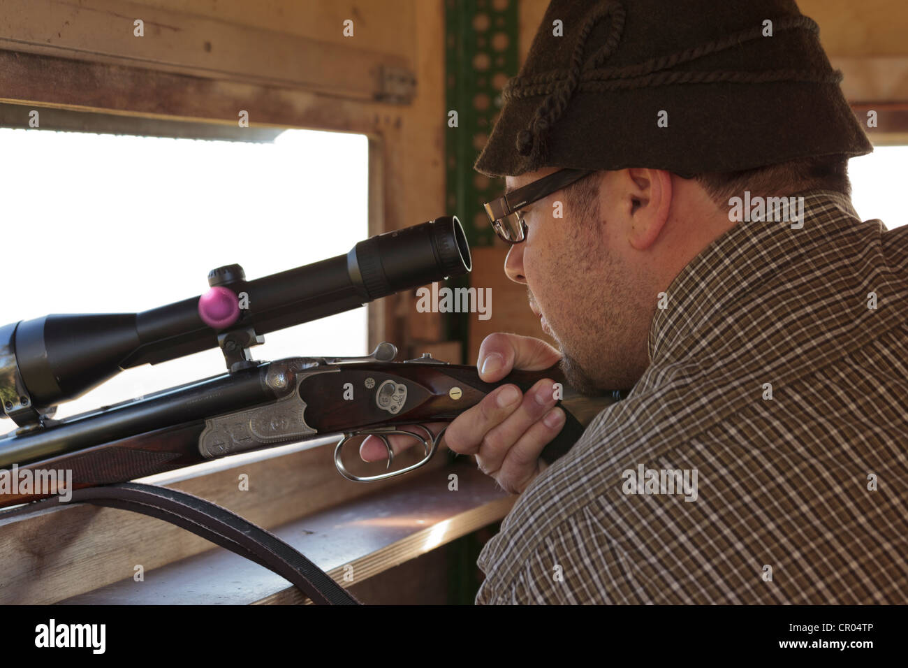 Hunter sitting on a deerstand, rifle at the ready Stock Photo - Alamy