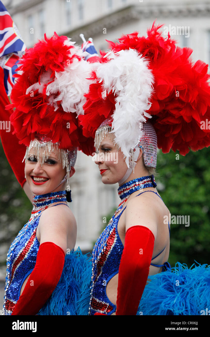Two show girls with feather headdresses and shiny union jack costumes ...