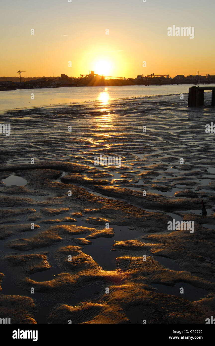 Sun setting behind mud beds on the River Thames in London, England ...