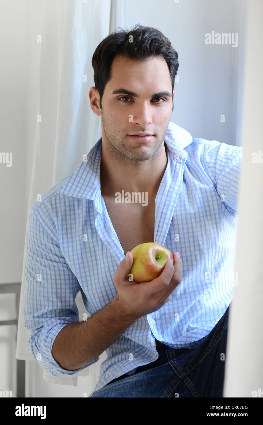 Young man sitting on a window sill eating an apple Stock Photo - Alamy
