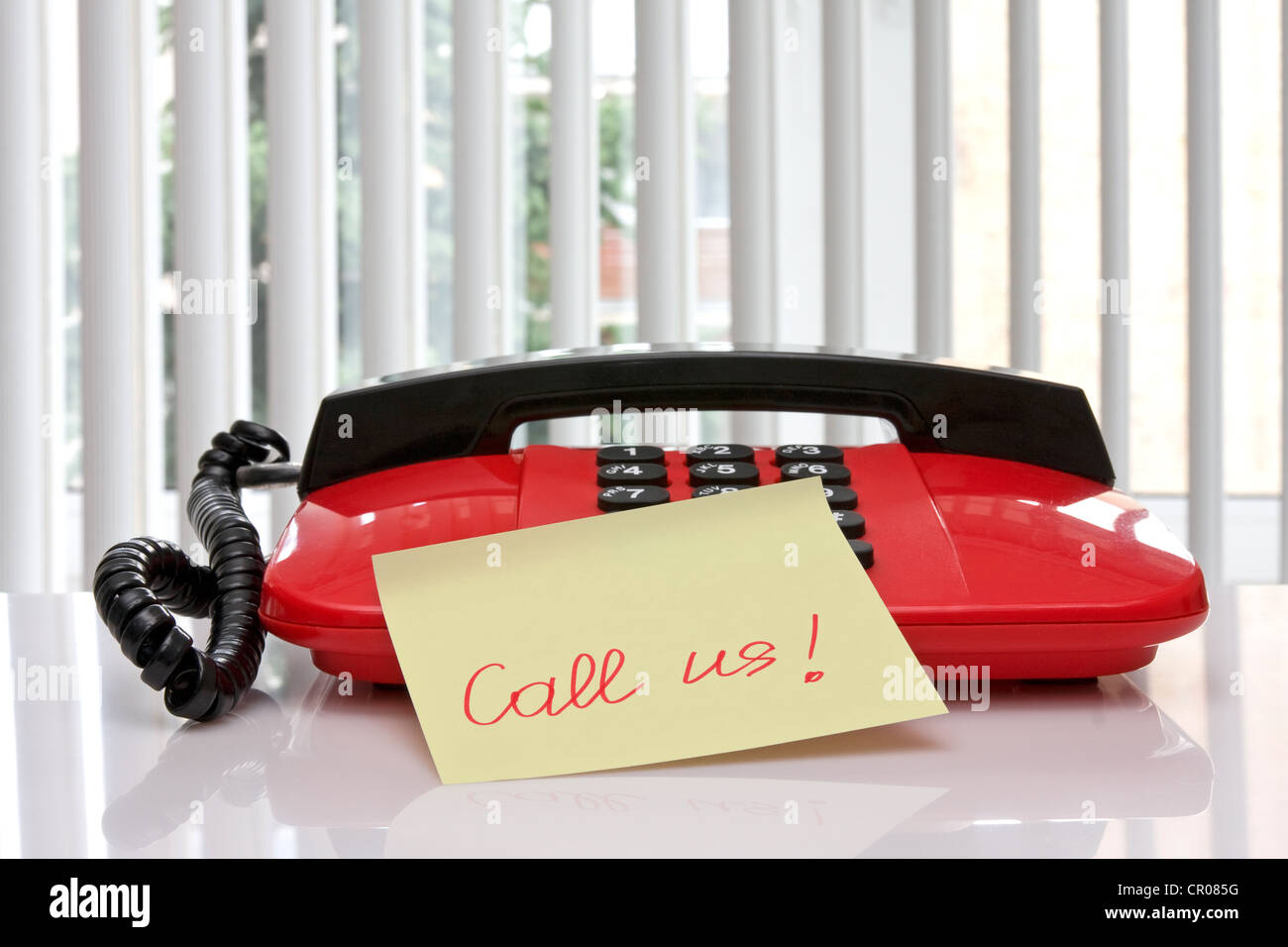 red office telephone with paper reminder "call us! Stock Photo - Alamy