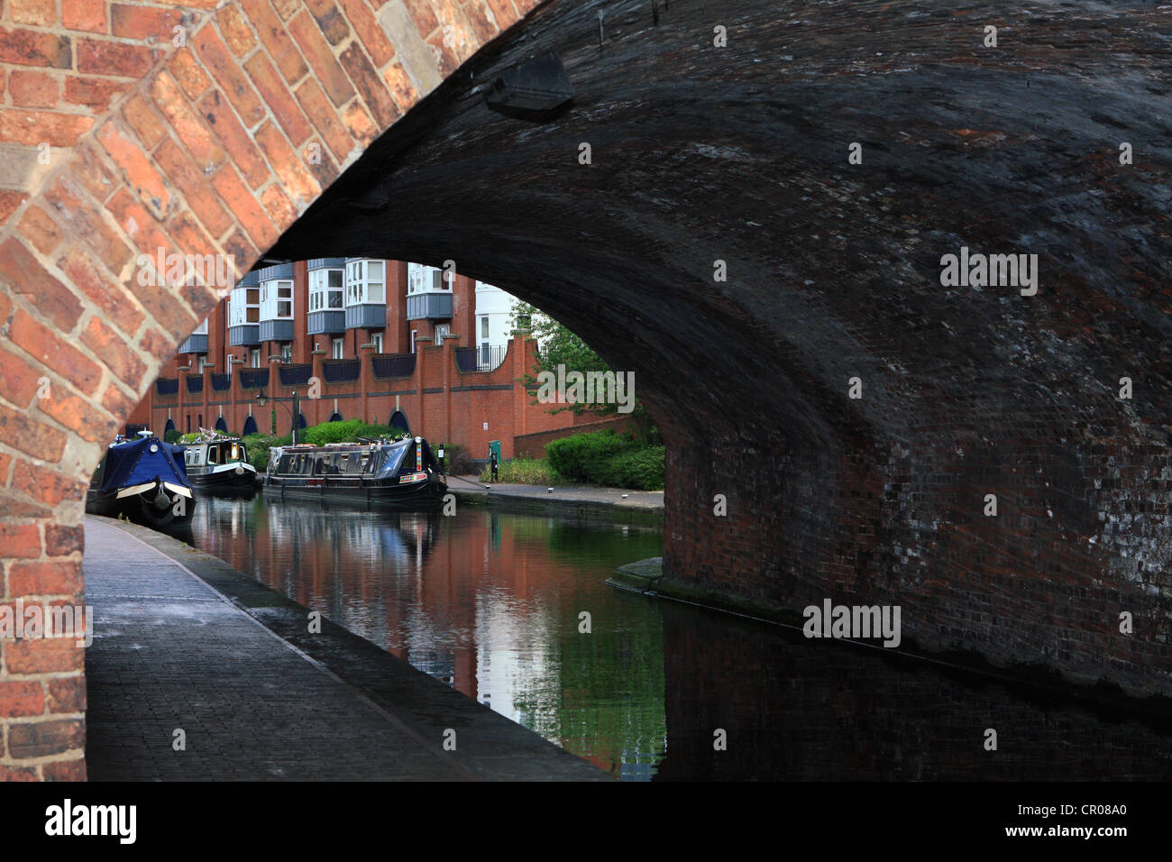 A view underneath a bridge to canal boats and buildings on the other ...