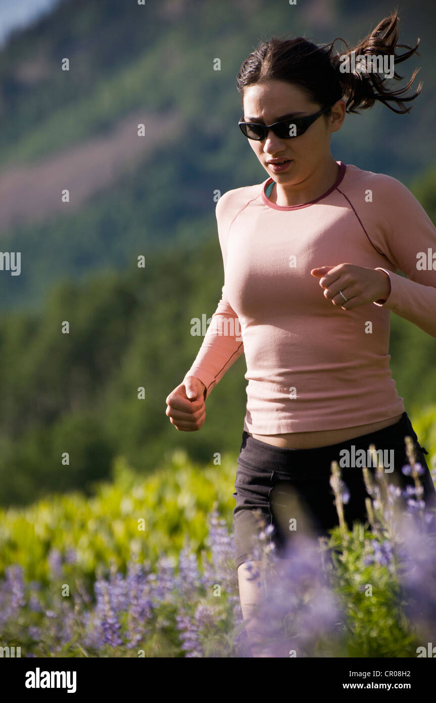 Woman running in field of flowers Stock Photo - Alamy