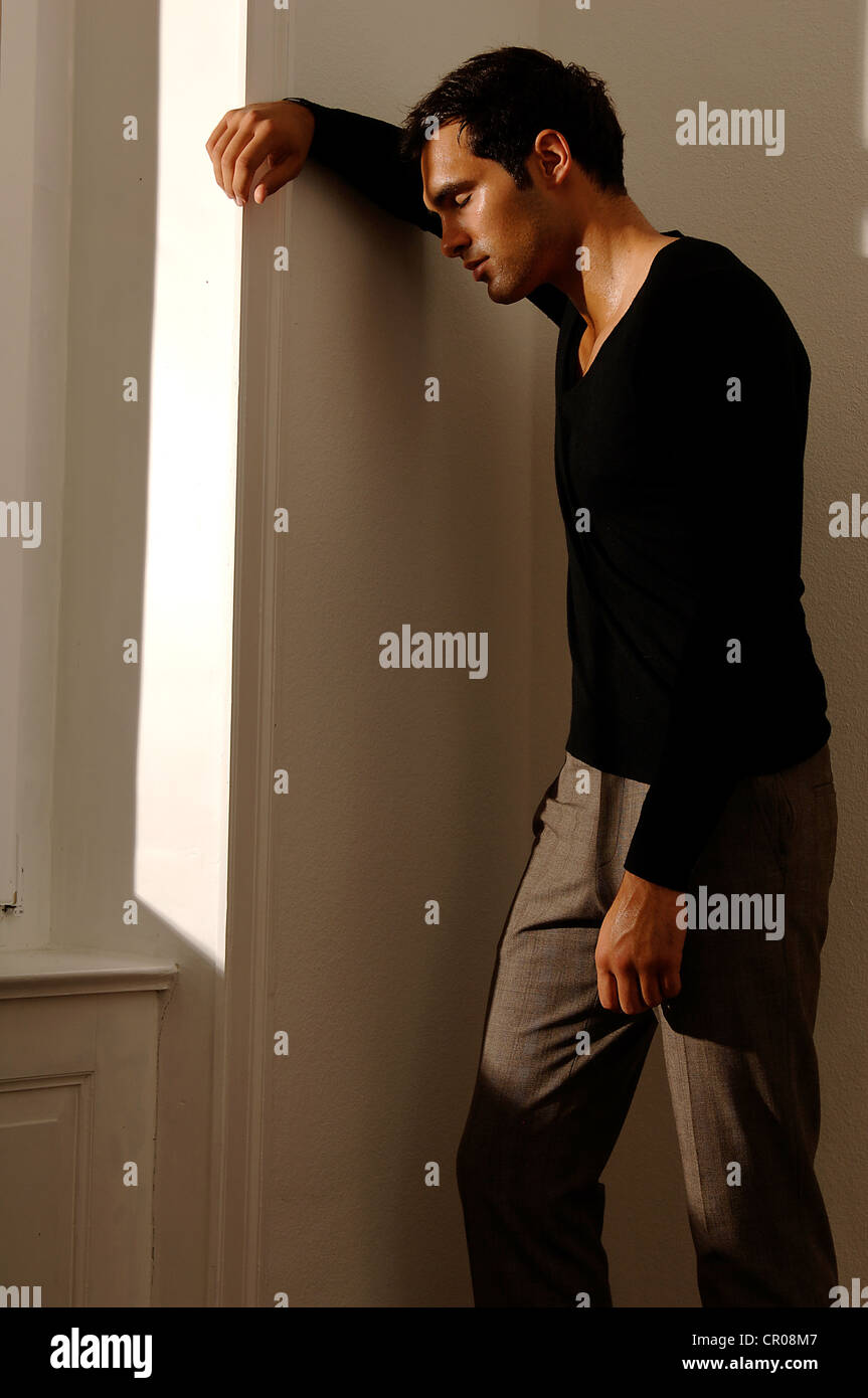 Young man leaning against apartment wall Stock Photo - Alamy