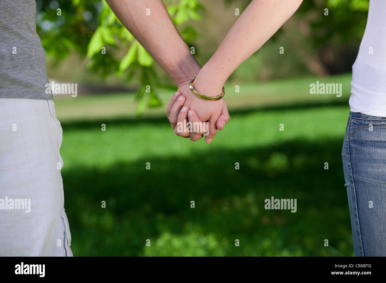 Young couple holding hands in a park in spring Stock Photo - Alamy