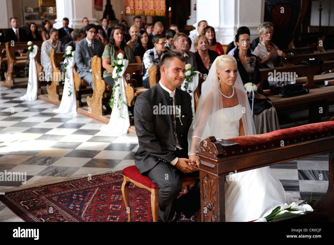 Bridal couple sitting in church in front of the wedding party Stock ...
