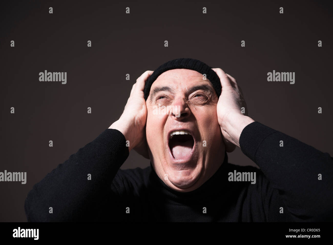 Screaming elderly man wearing a black woollen hat Stock Photo - Alamy