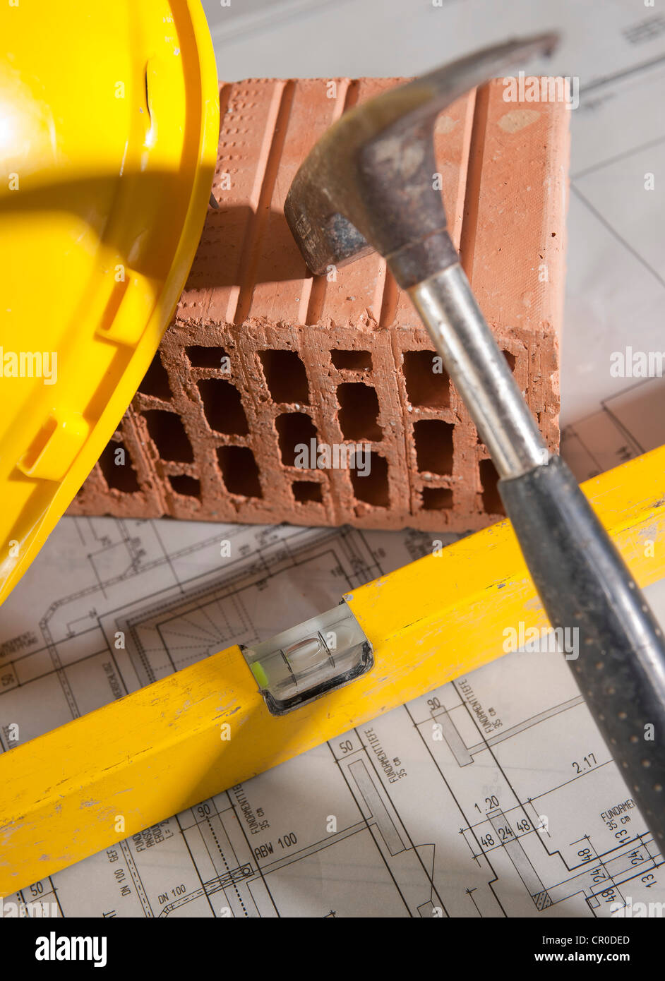 Safety helmet, spirit level, hammer and a brick on a building plan ...