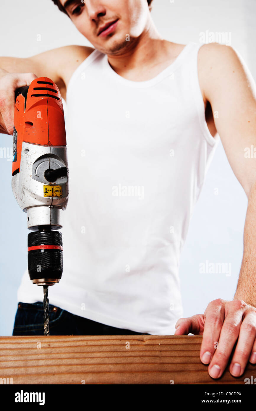 Young man drilling with a drill Stock Photo - Alamy