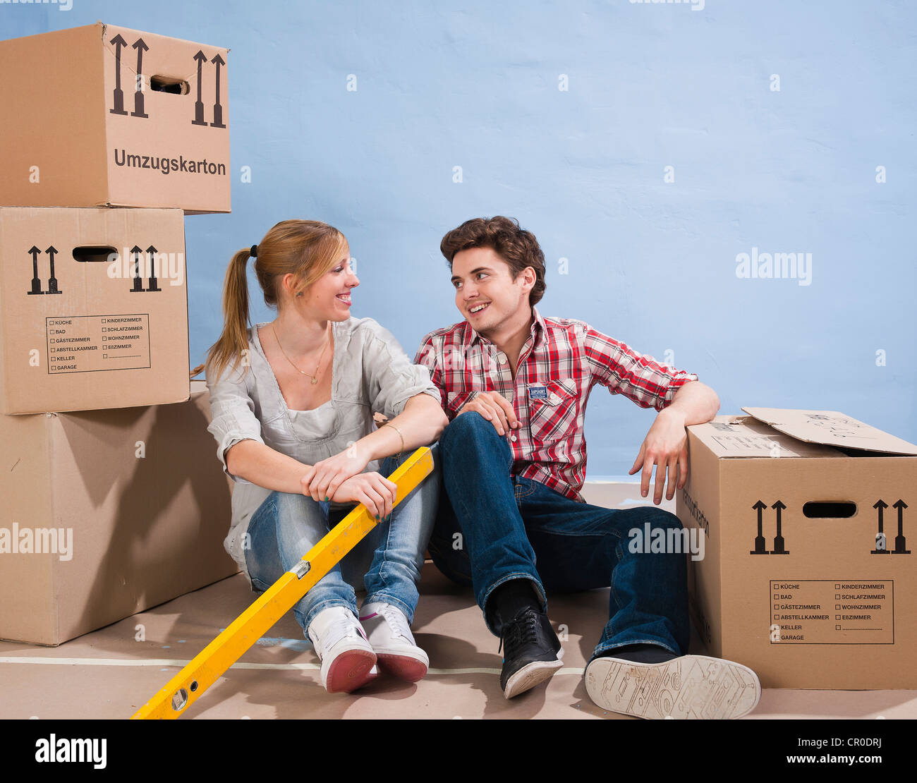Young couple sitting between packing boxes Stock Photo - Alamy