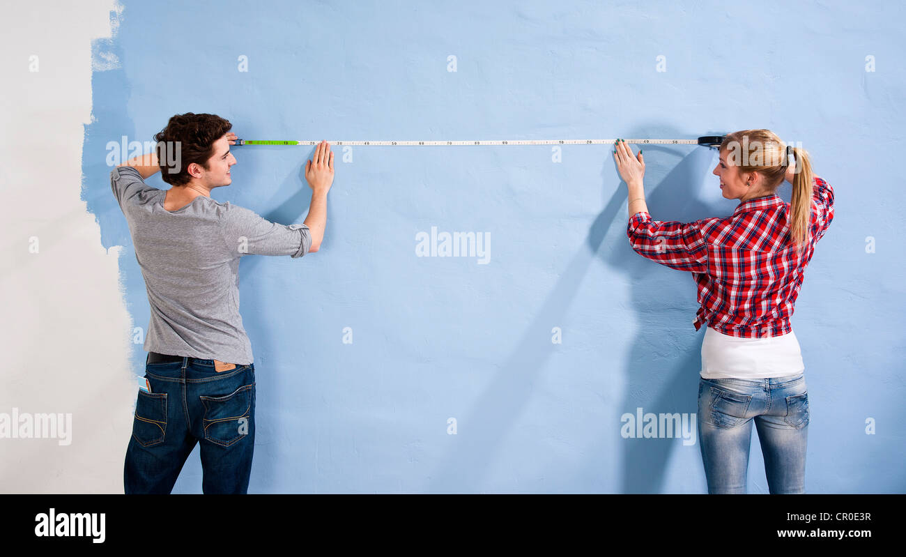 Young couple measuring a wall Stock Photo - Alamy