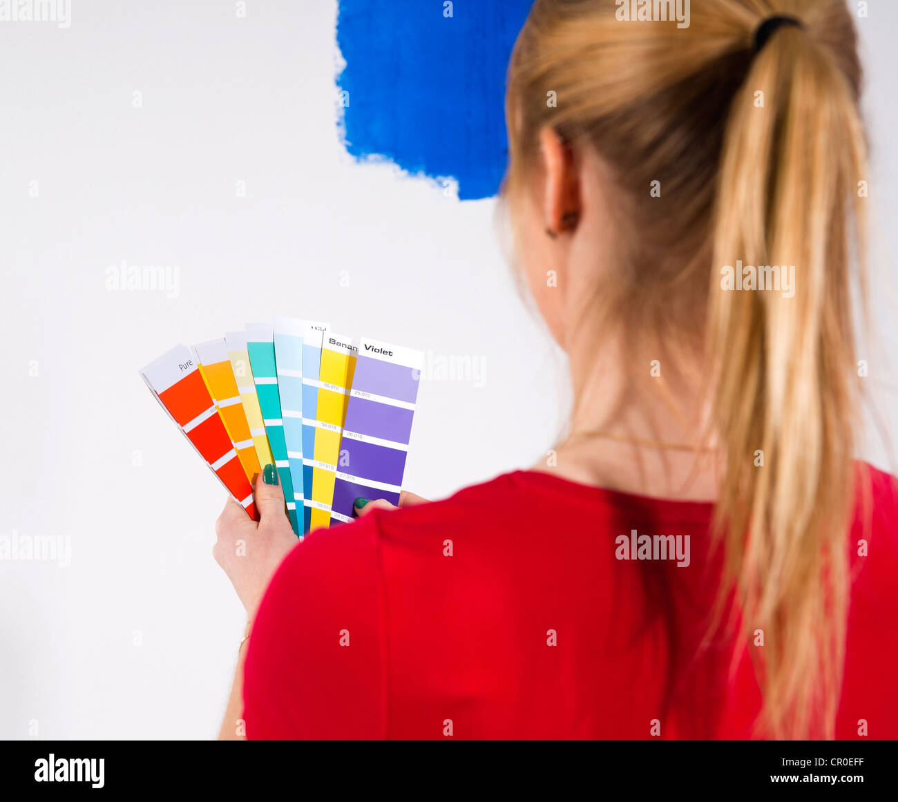 Young woman holding colour cards in front of a wall Stock Photo - Alamy