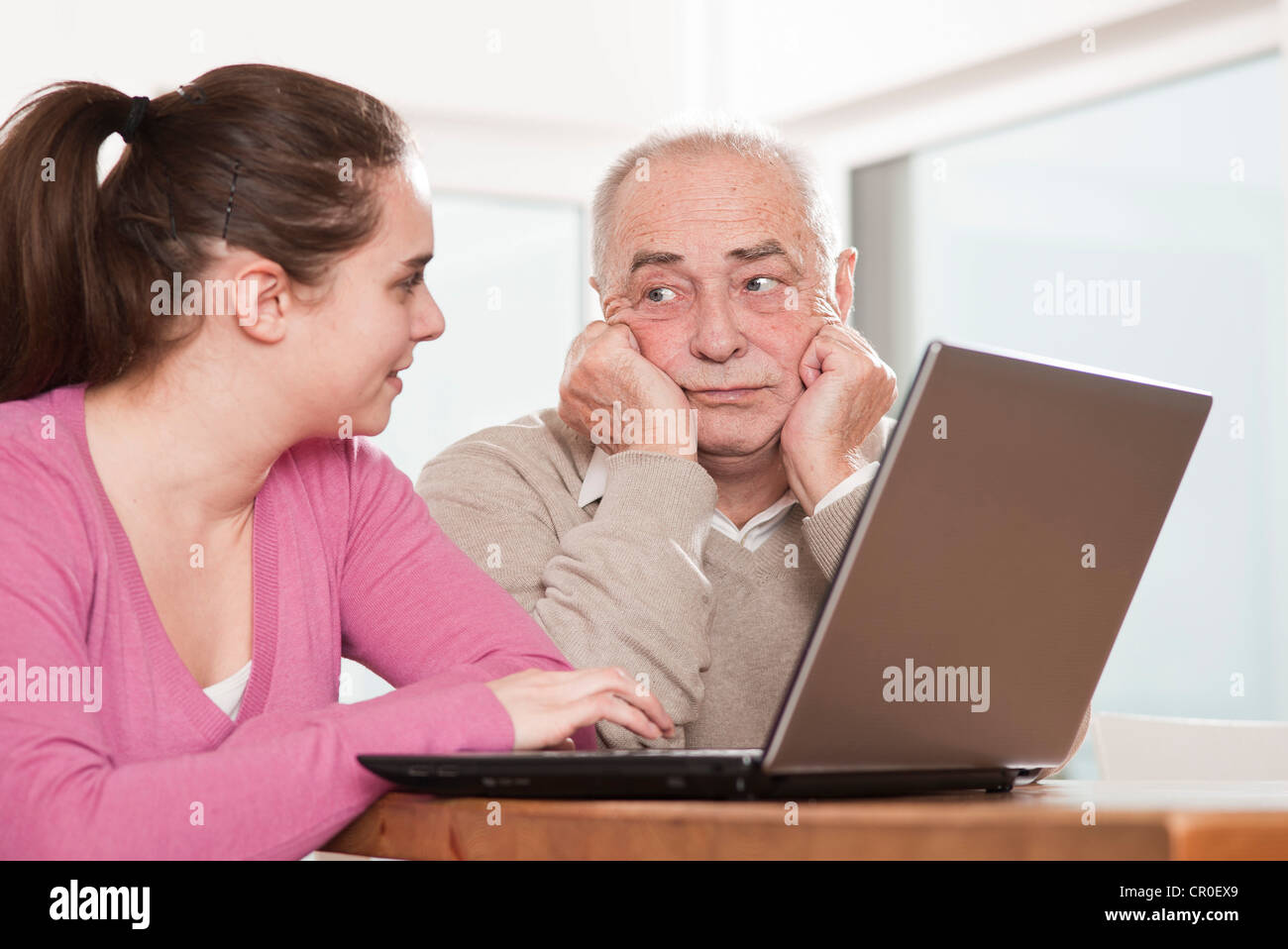 Young woman explaining the computer to an elderly man Stock Photo - Alamy