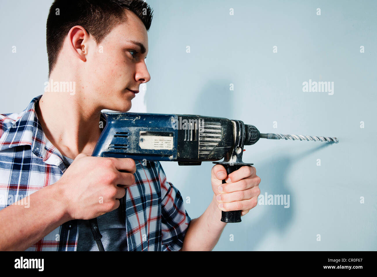 Young man using a drill Stock Photo - Alamy