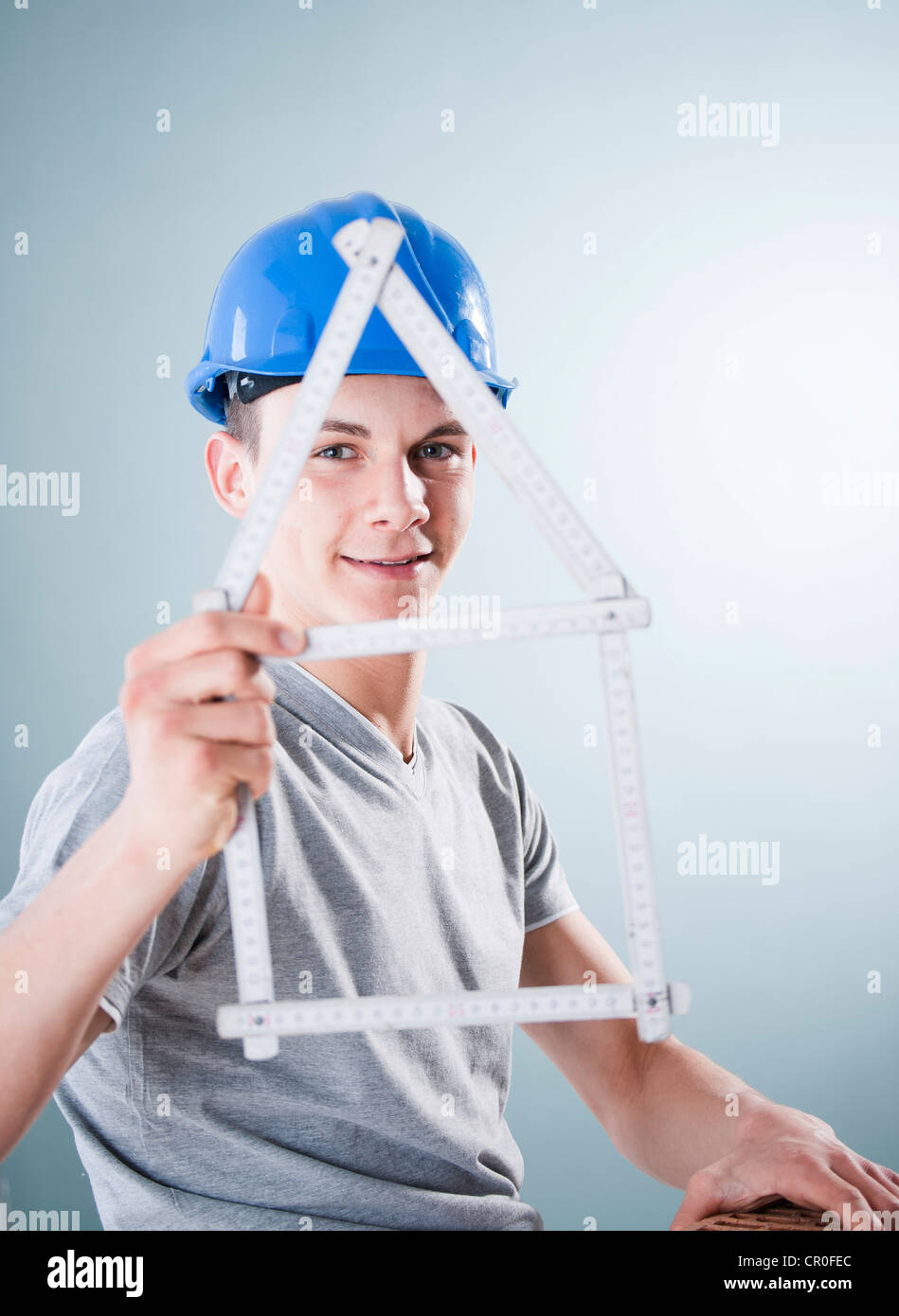 Young tradesman holding a folding carpenter's ruler in the shape of a ...