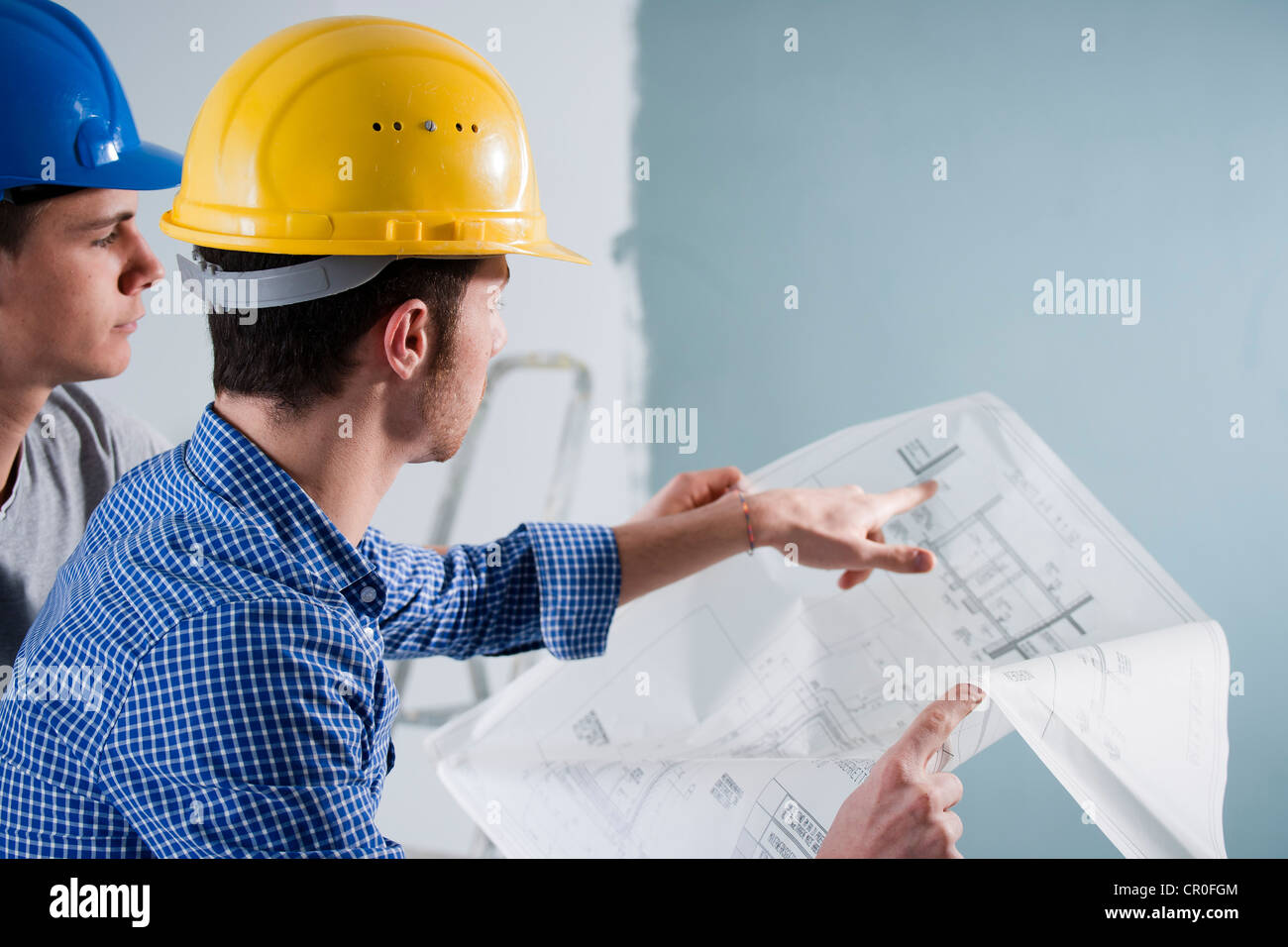 Two young tradesmen looking at a building plan Stock Photo - Alamy