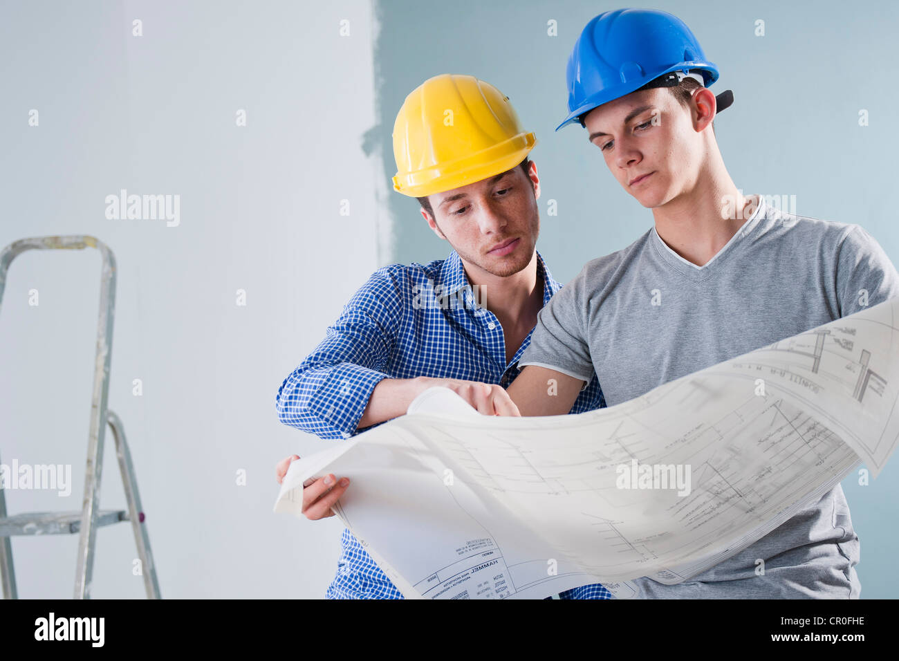 Two young tradesmen looking at a building plan Stock Photo - Alamy