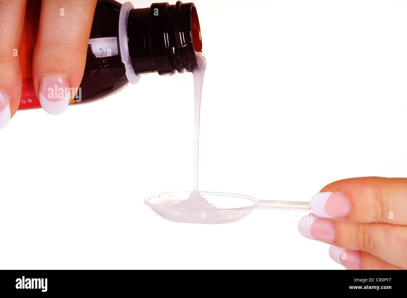 Liquid medicine pouring by female hands from bottle to measuring spoon ...