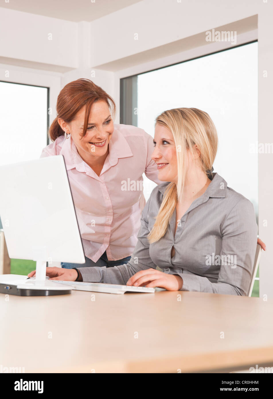 Two women working together on a computer Stock Photo - Alamy
