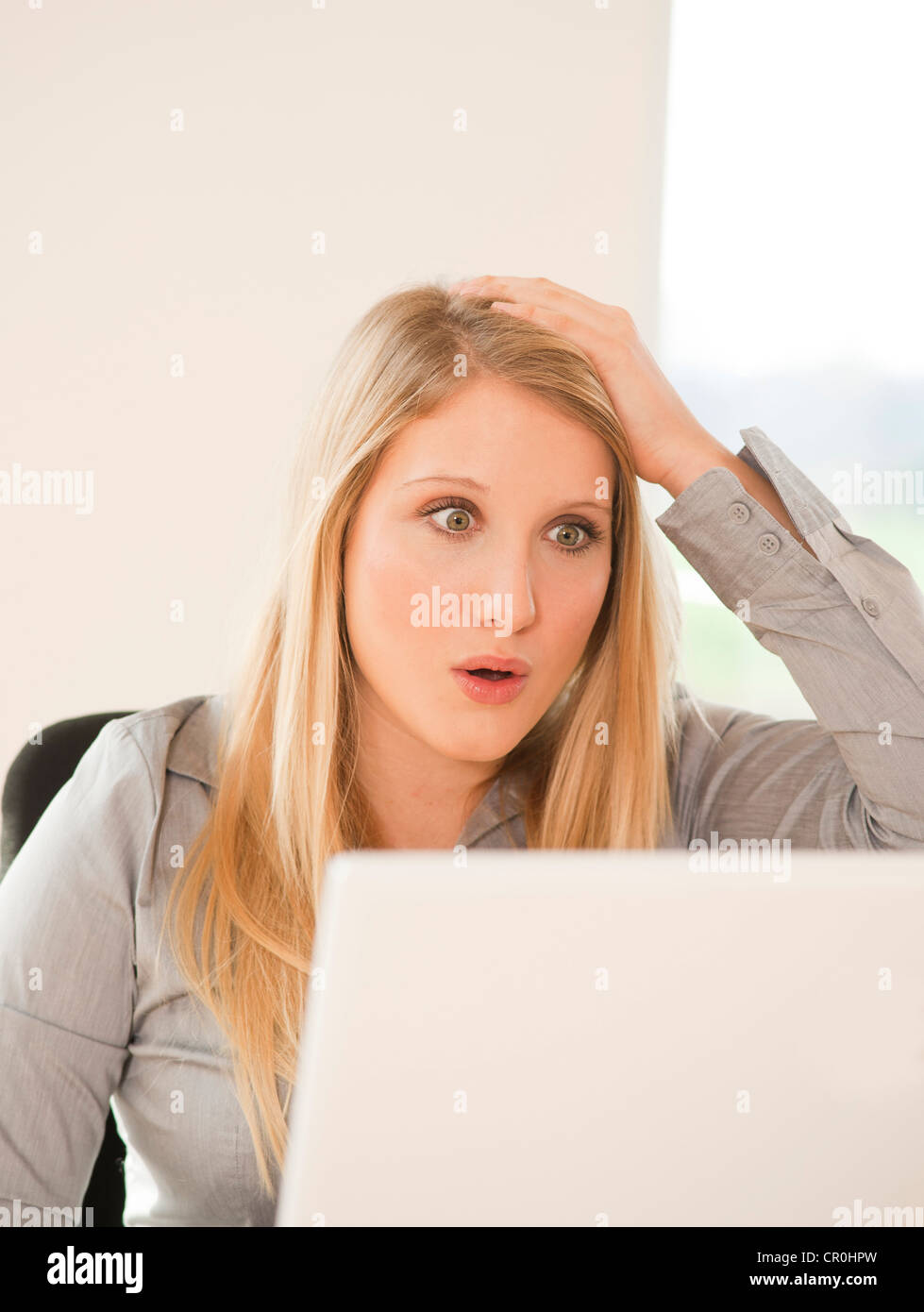 Young woman working on computer, shocked, surprised Stock Photo - Alamy
