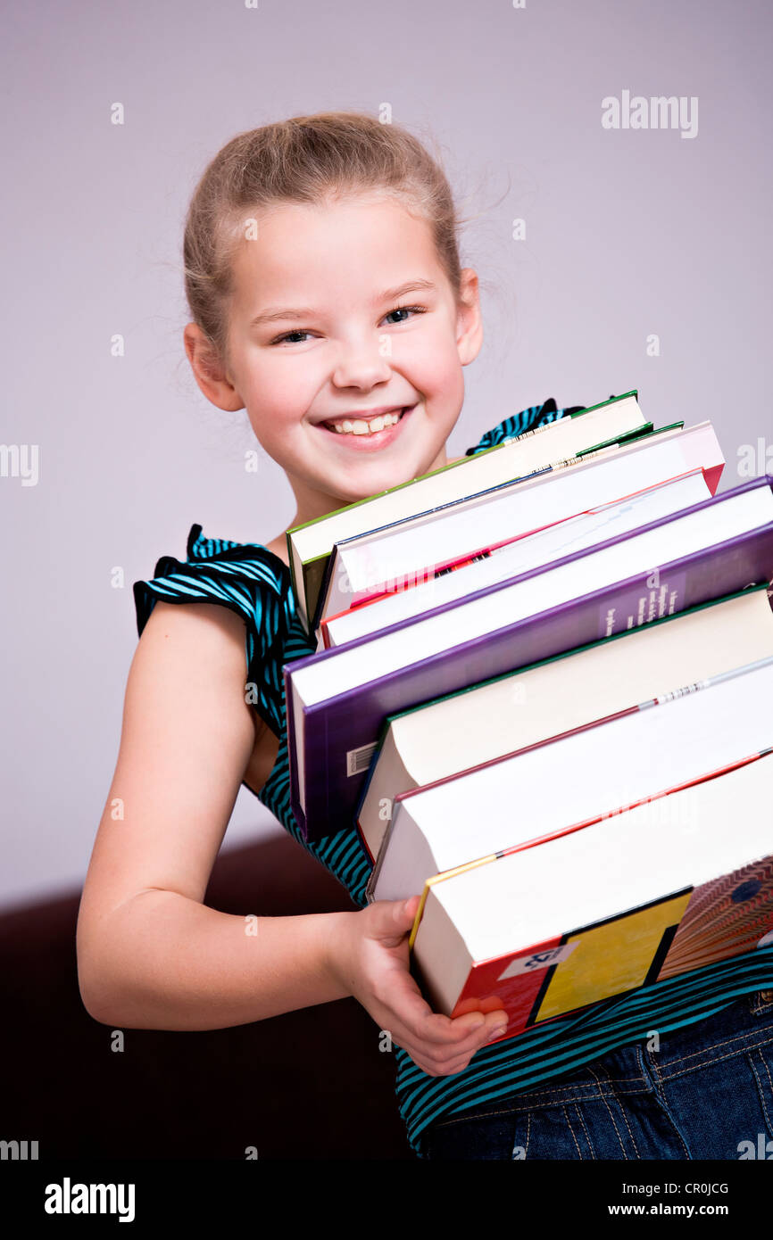 Girl, 8, carrying a stack of books Stock Photo - Alamy