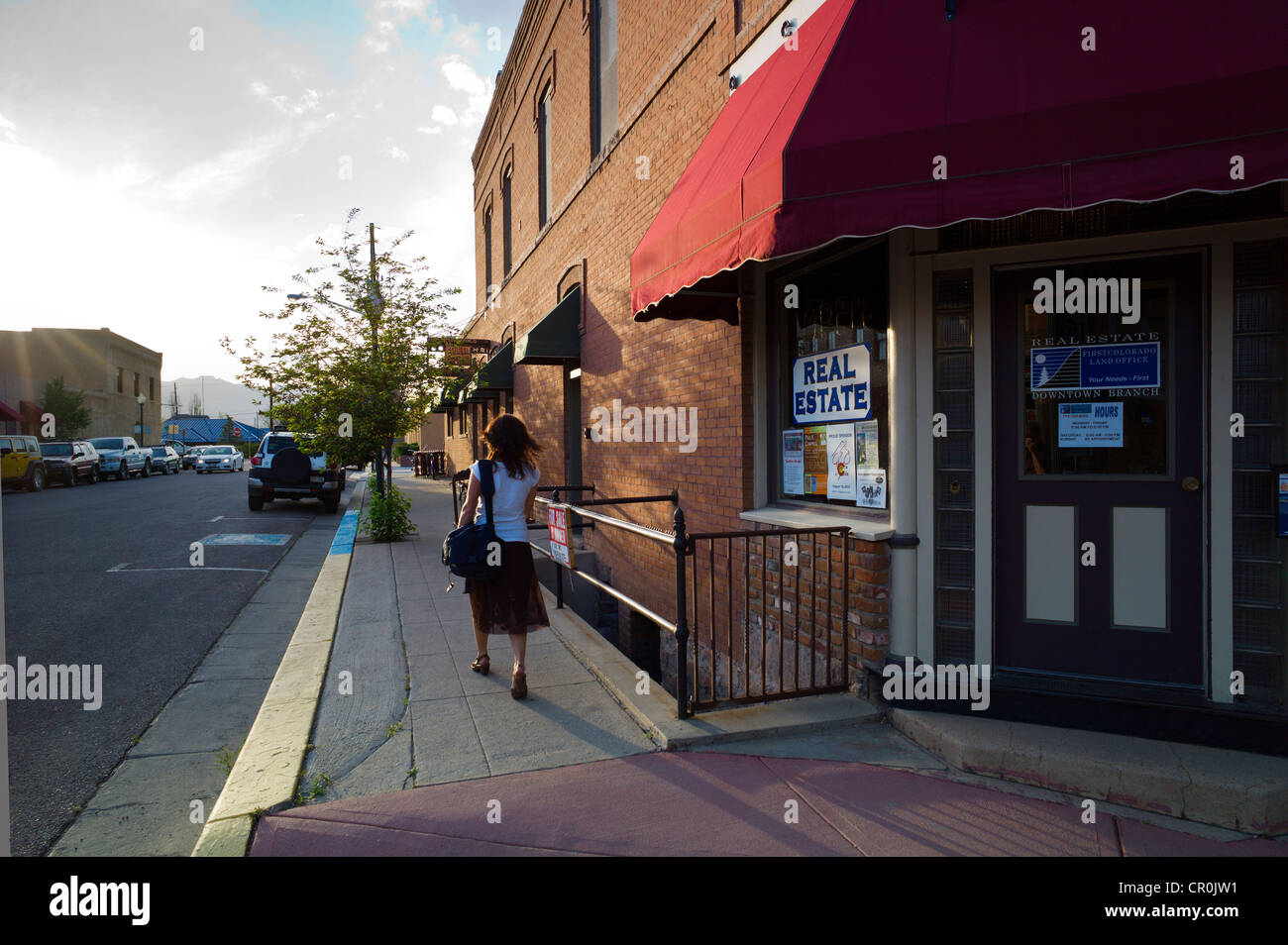 Woman strolling through historic downtown district at sunset, small ...