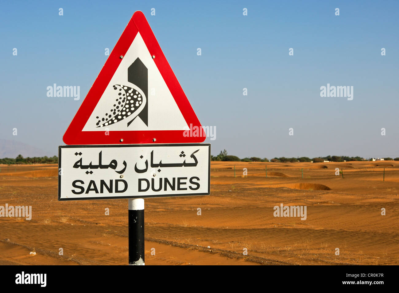 Road sign in English and Arabic warning of shifting sand dunes at a ...