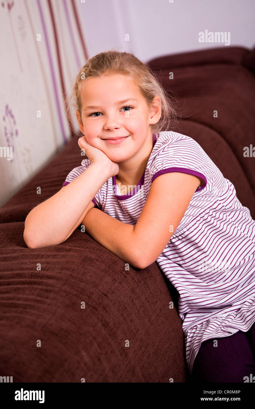 Girl, 8, sitting on a sofa Stock Photo - Alamy