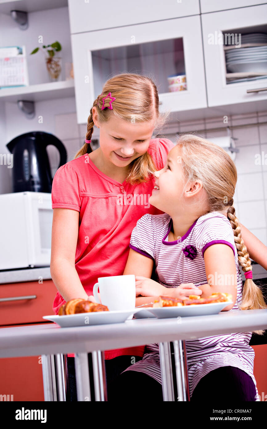 Two girls, sisters having breakfast in the kitchen Stock Photo - Alamy