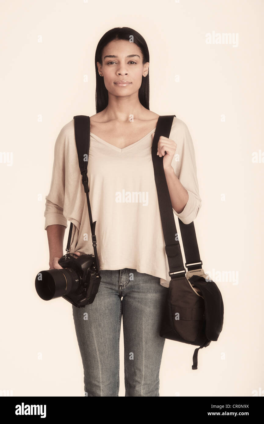 Studio portrait of woman carrying camera with bag Stock Photo - Alamy