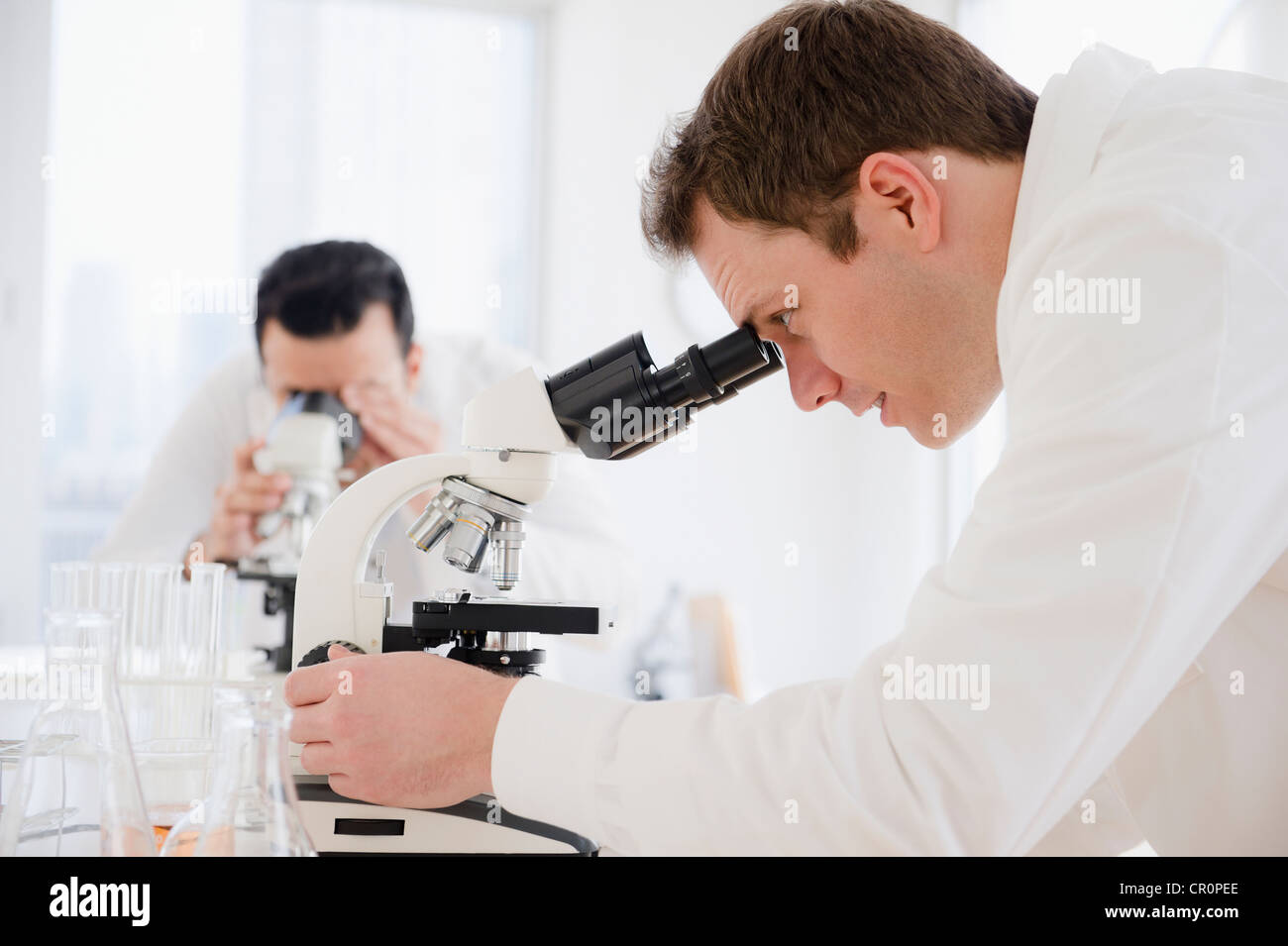 Caucasian scientist peering into microscope Stock Photo - Alamy
