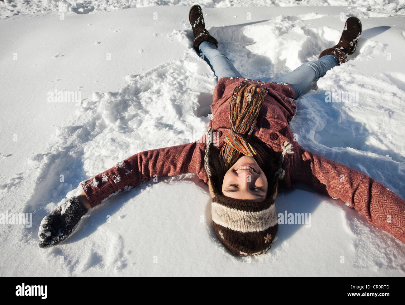 Caucasian woman making snow angel Stock Photo - Alamy