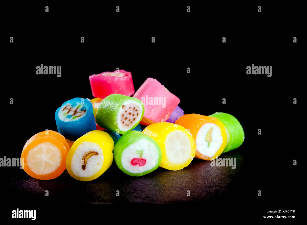 Lollies in different colors with fruit symbols over black in shallow ...