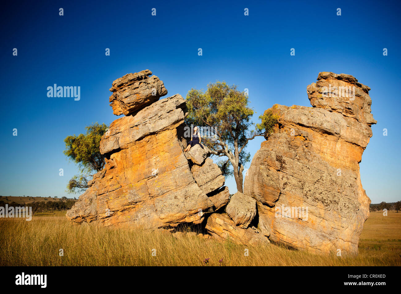 Young woman in a dress with two rocks split apart with a tree Stock ...