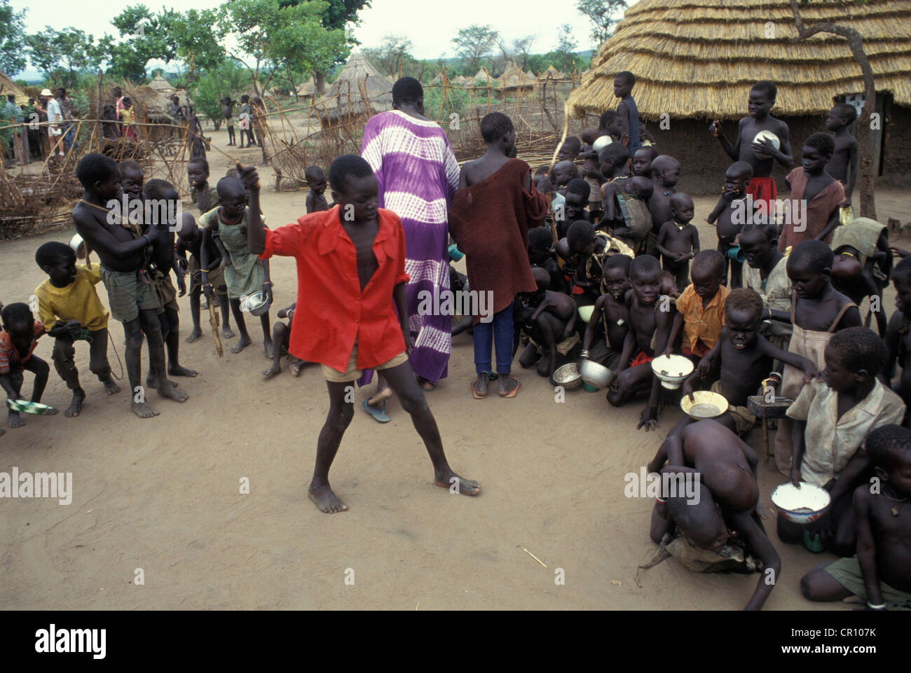 A Dinka boy beats other children into place at a feeding station for ...