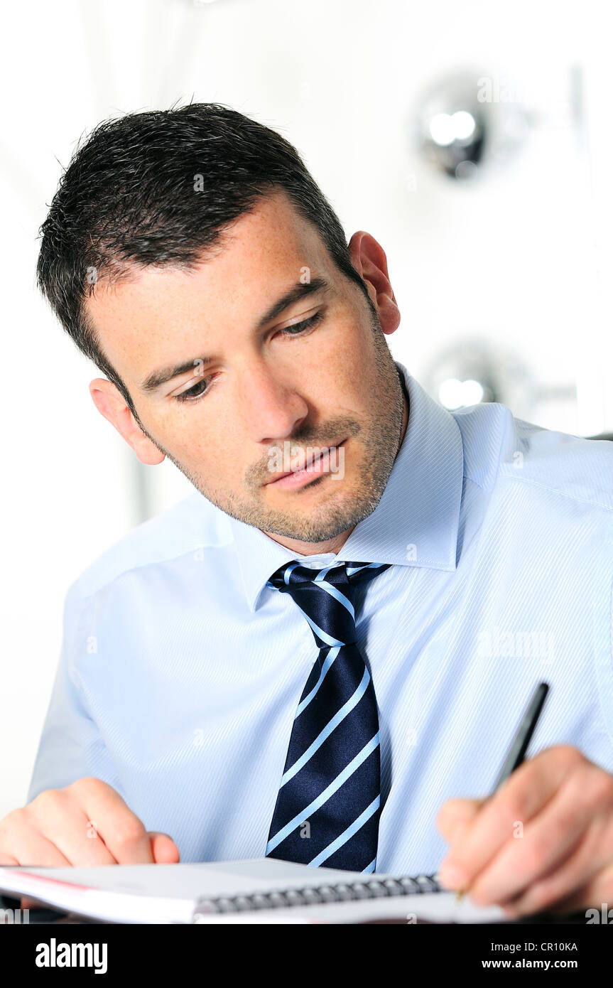 An attractive business man is writing on a paper Stock Photo - Alamy