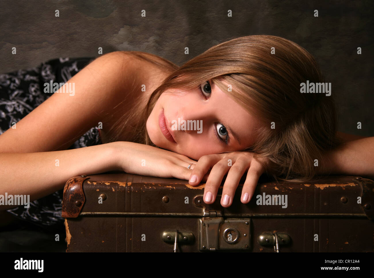Sad girl with old suitcase in studio Stock Photo - Alamy